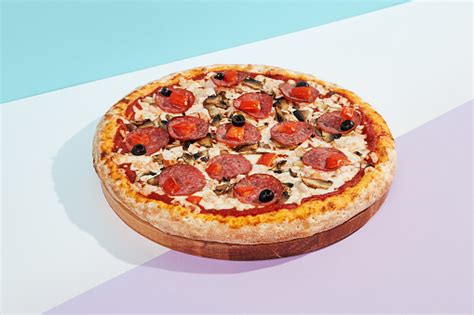 살라미 버섯 검은 올리브가 컬러 배경에 들어간 이탈리아 피자 살라미와 올리브가 들어간 고기 피자는 파란색과 보라색의 최소 스타일입니다 컬러 배경을 가진 미국 피자 배달 개념