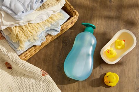 소박한 개념의 베이비 케어 테마 빈 라벨 파란색 병은 아기 옷의 등나무 바구니로 장식 된 나무 배경에 고무 노란색 오리 옆에 놓여 있습니다 광고 및 복사 공간을 위한 공간