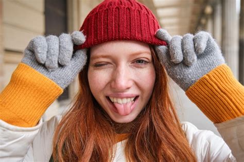 Premium Photo Portrait Of Young Redhead Woman In Knitted Hat And Gloves Smiles And Looks Aside