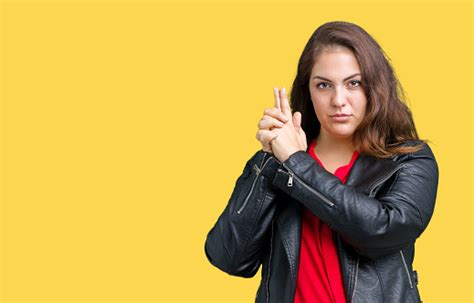 플러스 크기 젊은 여 자가 아름 다운 배경 손 제스처와 상징 총을 들고 사격 무기 성 난 얼굴을 죽이고 절연 이상 패션 가죽 자