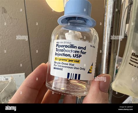 Persons Hand Holding A Vial Of Intravenous Iv Antibiotics From Sandoz Including Piperacillin