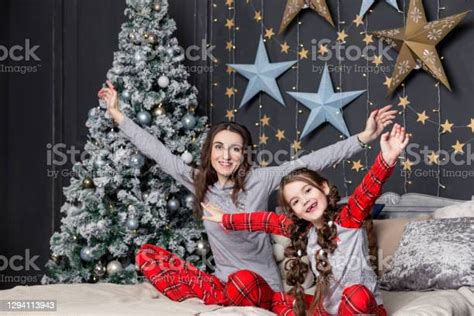새해 에 엄마와 딸은 크리스마스 트리의 배경에 침대에 잠옷과 함께 공중에 손을 들고 미소를 지었다 12월에 대한 스톡 사진 및 기타 이미지 Istock