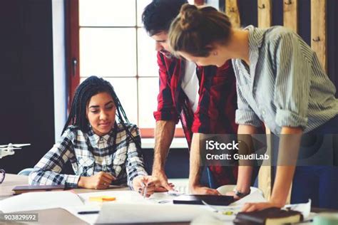 전문 남성과 여성 건축가 젊은 연수생 학생을 개선 하는 방법을 설명 하는 실수와 아침 회의 사무실에서 작업을 확인 하는 장점에 대해 얘기 하는 계획 청사진 연수생에 대한