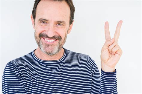 승리 표시를 하 고 카메라에 윙크 하는 행복 한 얼굴로 웃 고 고립 된 배경 위에 잘생긴 수석 남자 번호 2입니다 긍정적인 감정 표현에 대한 스톡 사진 및 기타 이미지