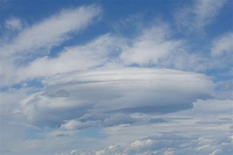 A Striking Circular Cloud Formation Is Visible Against A Bright Blue Sky Filled With Soft White