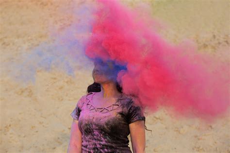 사막에서 분홍색과 파란색 건조 홀리 파우더와 함께 즐거운 시간을 보내는 긴 물결 모양의 머리를 가진 예쁜 갈색 머리 여자 감정에