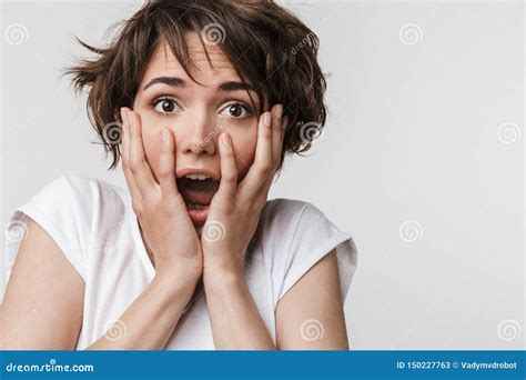 Фото шокированной женщины с короткими коричневыми волосами в базовой футболке держащей руку на