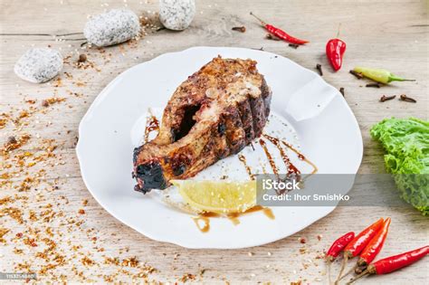 밝은 나무 테이블에 허브와 향신료와 흰 접시에 구운 생선 스테이크에서 보기를 닫습니다 메뉴 또는 조리법에 대 한 해산물 텍스트의 공간을 복사 합니다 0명에 대한 스톡 사진