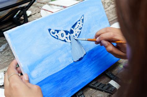 클로즈업 붓을 들고 있는 아시아 여성 화가 네 모서리의 나무 천에 고래와 바다를 칠하십시오 교사에게 보내기 전에 색상을 아름답게