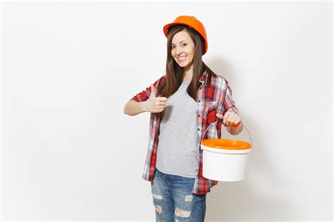 복사 공간을 가진 빈 페인트 통을 들고와 보여주는 엄지손가락에 고립 된 흰색 배경에 최대 보호 Hardhat에 젊은 웃는 여자 재건축 아파트 룸 악기입니다 수리 가정