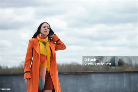 오렌지 망 토와 흐린 하늘 배경에 수조의 밝은 스카프에 검은 곱슬 머리와 함께 화려한 여자의 초상화 여 자가 거리에서 봐 꿈이 아름 다운 여성의 눈의 시선 갈색 머리에 대한