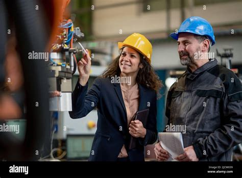 Female Engineering Manager And Mechanic Worker Doing Routine Check Up In Industrial Factory