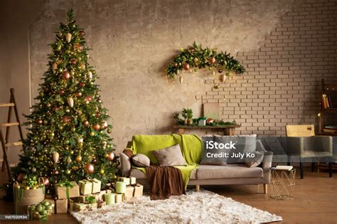 스튜디오 아파트의 현대적인 크리스마스 거실 인테리어 대형 장식 된 크리스마스 트리 소파 격자무늬 선물 상자 푹신한 카펫 가벼운 화환 트렌드 컬러 2022 그린 커피 베이지