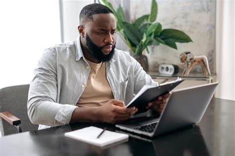 문서 작업에 집중하는 영리한 아프리카계 미국인 바쁜 사업가 회사 Ceo는 프로젝트 작업을 하는 현대적인 사무실의 책상에 앉아