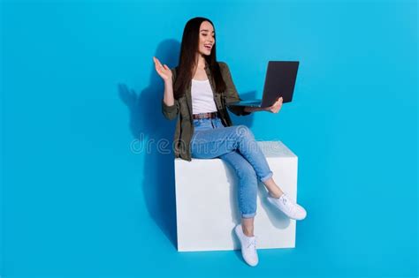 Trendy Young Woman Using A Laptop While Sitting On A White Block With A
