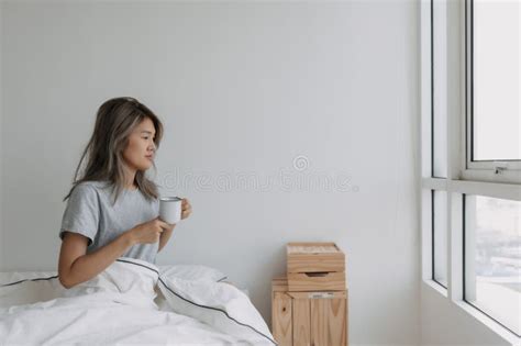 Woman Drinking Coffee Right After Wake Up On The Bed In The Morning
