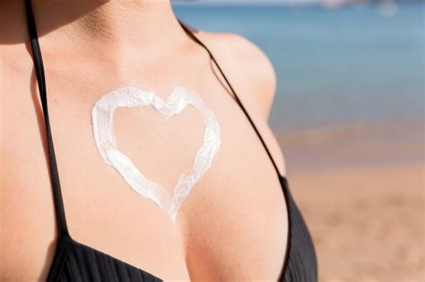 Premium Photo Tanned Woman With Heart Shaped Sun Cream On Her Breast