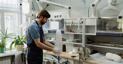 작업장에서 모양을 형성하고 고정하기 위해 보철 소켓의 공작물에 흰색 시트를 씌우는 제조소 작업자 사진 Unsplash의 공장 이미지