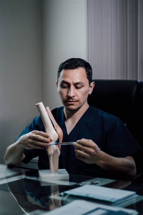 Free Professional Doctor Explaining Knee Anatomy With Model In Office