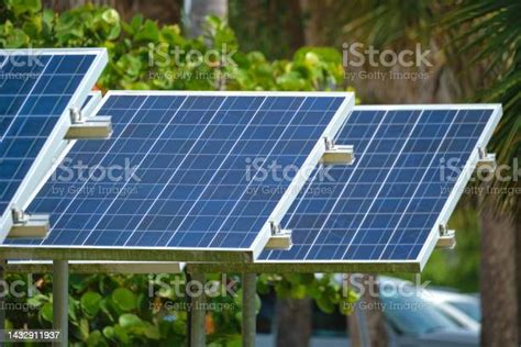 깨끗한 전기의 효과적인 생성을 위해 주차장 근처의 스탠드 프레임에 설치된 태양 전지판 전기 자동차 충전을위한 도시 인프라에 통합 된 태양 광 기술 설치미술에 대한 스톡 사진