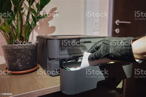 검은 장갑을 끼고 있는 남자는 손전등의 야간 조명에서 프린터에서 종이 한 장을 가져온다 컴퓨터 프린터에 대한 스톡 사진 및 기타 이미지 컴퓨터 프린터 보안 사무실