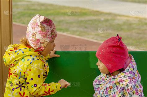 三岁和两岁的小女孩中午在操场上聊天。