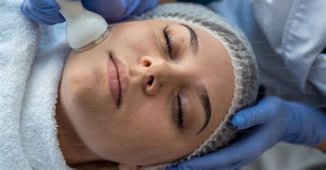 미용사로부터 각질 제거 회춘 및 수분 공급으로 전문적인 절차를 받는 젊은 여성 얼굴 피부 초음파 캐비테이션 사진