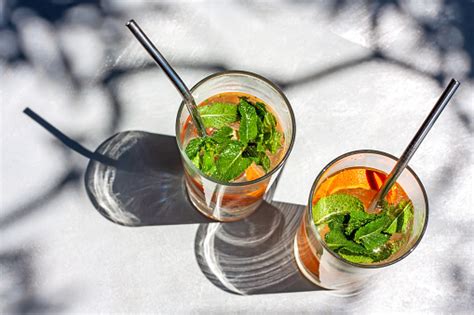 차가운 상쾌한 여름 음료 레모네이드 에 금속 빨대 와 안경 금속 재활용 빨대가 있는 유리에 오렌지와 민트 조각을 곁들인 해독물 또는 오렌지 칵테일 여름 제로 와트 개념 맨