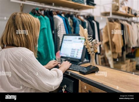 Female Store Employee From Behind At The Counter Looking At The Store