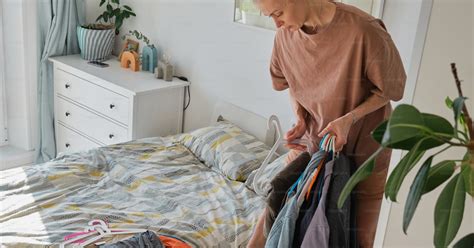 옷 더미가 있는 침대 옆에 서 있는 여자 사진 Unsplash의 리프레쉬 이미지