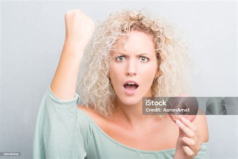 그런 지 그레이 통해 젊은 금발 여자 배경 화가 핑크 도넛 먹고 미친과 제기 손으로 소리 분노와 좌절 외치고 분노 개념 감정에 대한 스톡 사진 및 기타 이미지 Istock