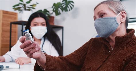 혼합 인종 약국 의사 여성은 클리닉 검사에서 수석 백인 환자 여성에게 백신 의학플라스크를 제공합니다 20 24세에 대한 스톡 사진 및 기타 이미지 Istock