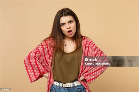 캐주얼 맹세에서 젊은 여자 충격 스튜디오에서 파스텔 베이 지 벽 배경에 고립 된 허리에 팔을 Akimbo에 서 사람들은 진심으로 감정 라이프 스타일 개념입니다 복사 공간을