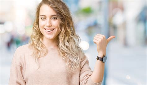 아름 다운 젊은 금발 여자 생기고 엄지 측면 가리키는 행복 한 얼굴로 웃 고 고립 된 배경 위에 Sweatershirt를 입고 가리키기에 대한 스톡 사진 및 기타 이미지