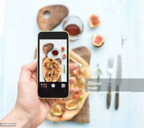 휴대 전화에서 촬영 손 소박한 집에서 만든 피자 무화과 프로 슈 토와 모 짜 렐 라 치즈 밝은 파란색 배경 위에 어두운 나무 서빙 보드 평면도 가을에 대한 스톡 사진 및