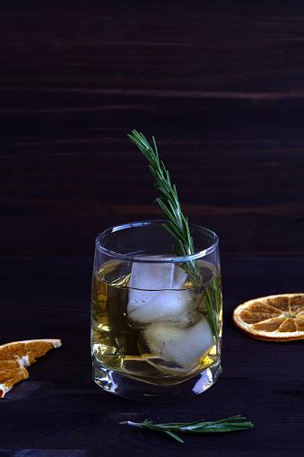 얼음 조각레모네이드 한 잔 위스키 또는 칵테일한 잔에 오렌지 조각을 얹은 얼음을 나무 테이블에 올려놓으세요 어두운 배경에 얼음과 로즈마리의 잔가지와 유리에 음료 0명에 대한