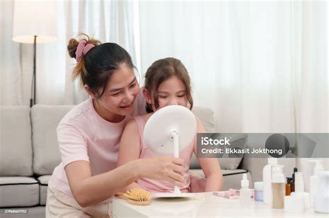 백인 딸과 아시아인 엄마가 거울 앞에서 함께 미소 짓는 행복 엄마는 거울을 들고 딸은 거울에 비친 모습을 즐겁게 바라보며 아름다움과 자기 관리 루틴을 즐깁니다 2명에 대한