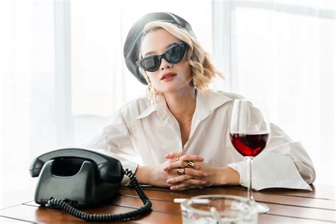 검은 베 레모와 레드 와인의 레트로 전화와 유리 근처에 앉아있는 선글라스에 우아한 금발 여자 금발 머리에 대한 스톡 사진 및 기타 이미지 Istock