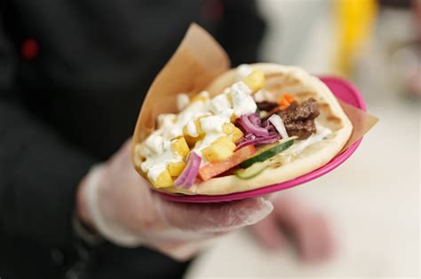 그리스 요리사는 식당에서 점심으로 전통적인 자이로 샌드위치를 준비했습니다 주방 노동자는 Tzatziki 소스와 고기로 포장 된 피타 수블라키 요리를 요리합니다 굽기에 대한