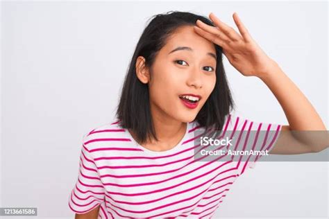 스트라이프 티셔츠를 입은 젊은 중국 여성은 고립 된 흰색 배경 위에 서매우 행복하고 머리 위에 손으로 멀리 보고 미소 개념 검색 T 셔츠에 대한 스톡 사진 및 기타 이미지