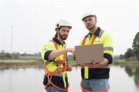 풍차 현장 농장에서 노트북 컴퓨터를 사용하여 안전 유니폼을 입고 풍력 터빈의 품질 검사 및 검사 풍력 터빈 수리 또는 유지 보수를 하는 남성 엔지니어 20 24세에 대한