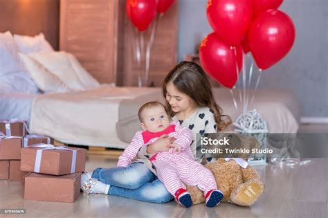 귀여운 아기 소녀는 빨간 풍선 가까이 함께 출산 일을 축 하 합니다 사랑 스러운 장면에 아기의 소파에 있는 디반와 함께 선물 및 빨간 Baloons 2명에 대한 스톡 사진