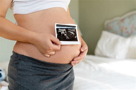 임신 한 여자는 그녀의 아이를 돌보는 동안 집에서 행복을 느낀다 임신 한 배에 아기를 들고 젊은 기대 어머니 출산 전 관리 및 여성 임신 개념 임신에 대한 스톡 사진 및