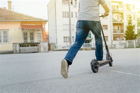 건물 앞의 여름 날 마당 아스팔트에 전기 킥 스쿠터를 타고 청바지에 선배의 백 뷰 전기 스쿠터에 대한 스톡 사진 및 기타 이미지 전기 스쿠터 노인 남자 타기 Istock
