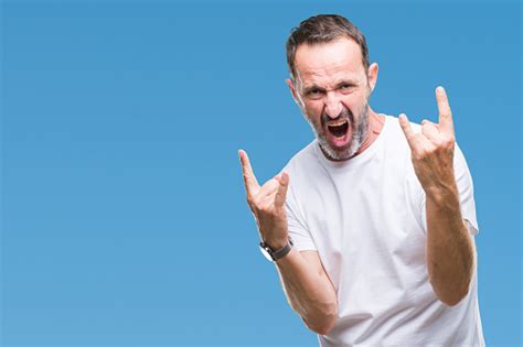 중 년 노인의 수석 사람 손으로 바위 상징 하 고 미친 식 소리 고립 된 배경 위에 흰색 T셔츠를 입고 음악 스타입니다 무거운 개념입니다 T 셔츠에 대한 스톡 사진 및 기타