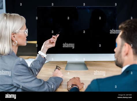 Selective Focus Of Computer Monitor With Blank Screen Near Businessman And Businesswoman Stock
