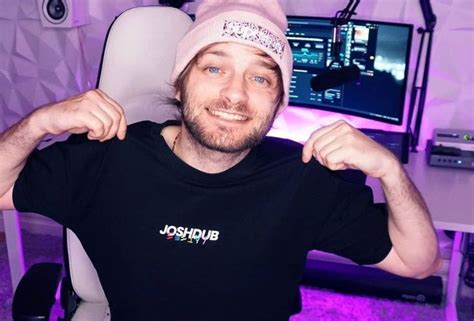 A Man Wearing A Beanie Sitting In Front Of A Computer Desk With A