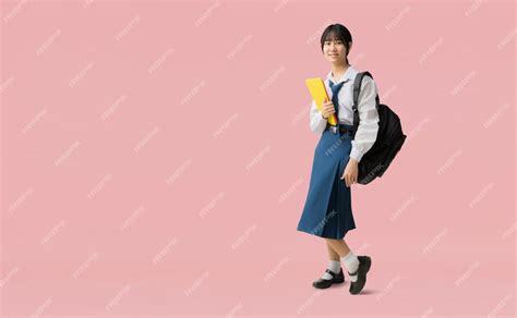디자인 작업을 위한 클리핑 패스를 사용하여 분홍색 배경에 격리된 유니폼을 입은 전신 아시아 여학생은 빈 여유 공간을 보유하고