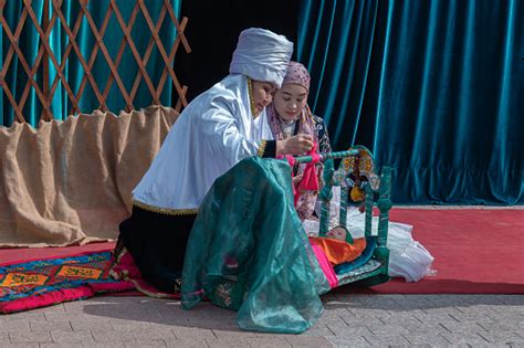 노령자 여성과 전국 카자흐 의상을 입은 어린 소녀가 거리 극장 공연 중 리본으로 전통적인 베식 침대를 장식합니다 카자흐스탄에 대한 스톡 사진 및 기타 이미지 Istock