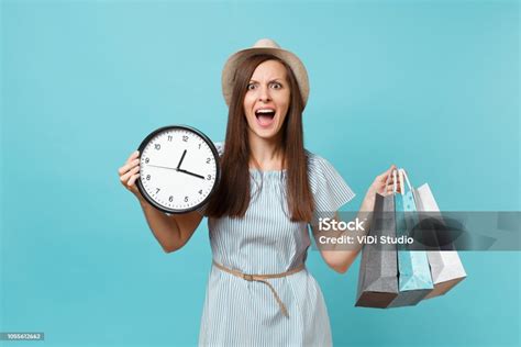 초상화 아름 다운 여름 드레스 밀 짚 모자 지주에 젊은 백인 여자 쇼핑 블루 파스텔 배경에 고립 시계 라운드 후 구매 가방